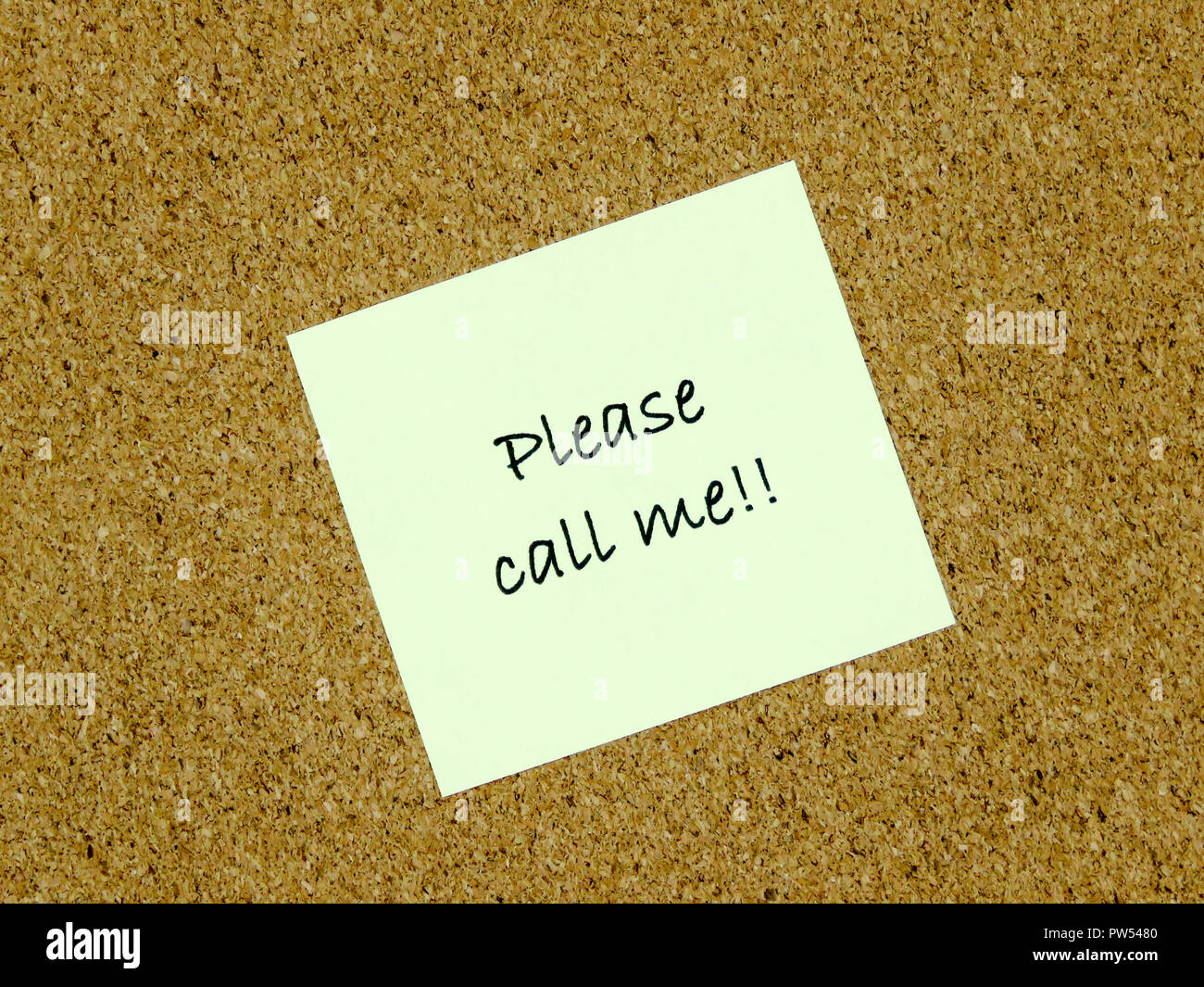 A yellow sticky note with please call me written on it on a cork board ...