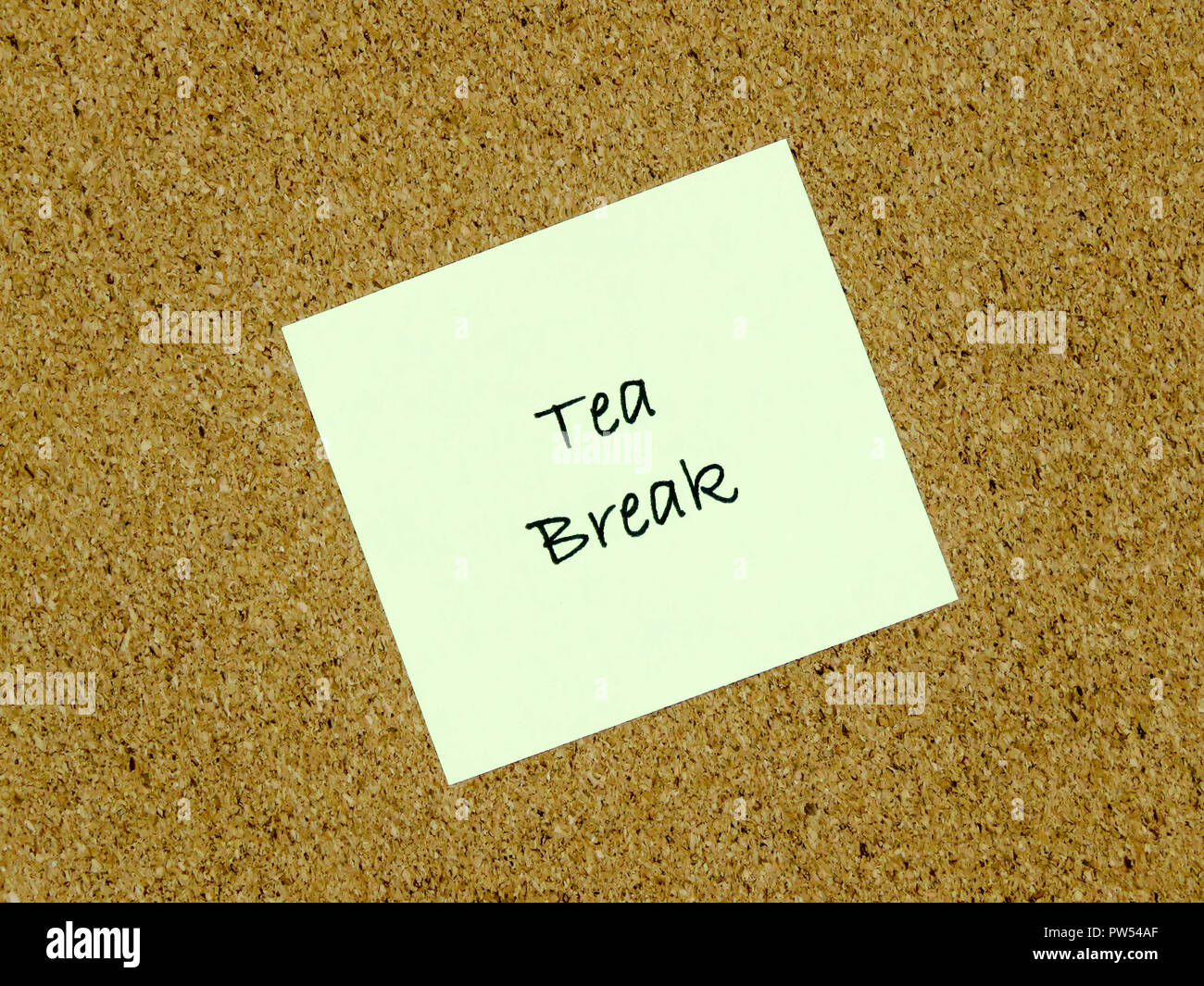 A yellow sticky note with tea break written on it on a cork board ...