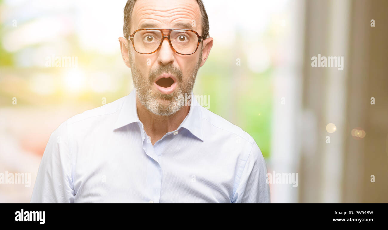 Middle age man with glasses scared in shock, expressing panic and fear ...