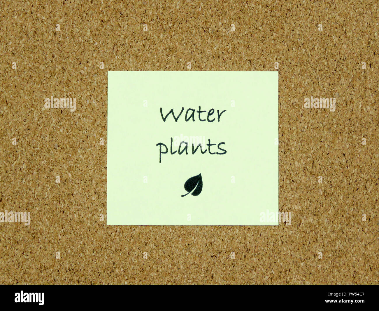 A yellow sticky note with water plants written on it on a cork board ...