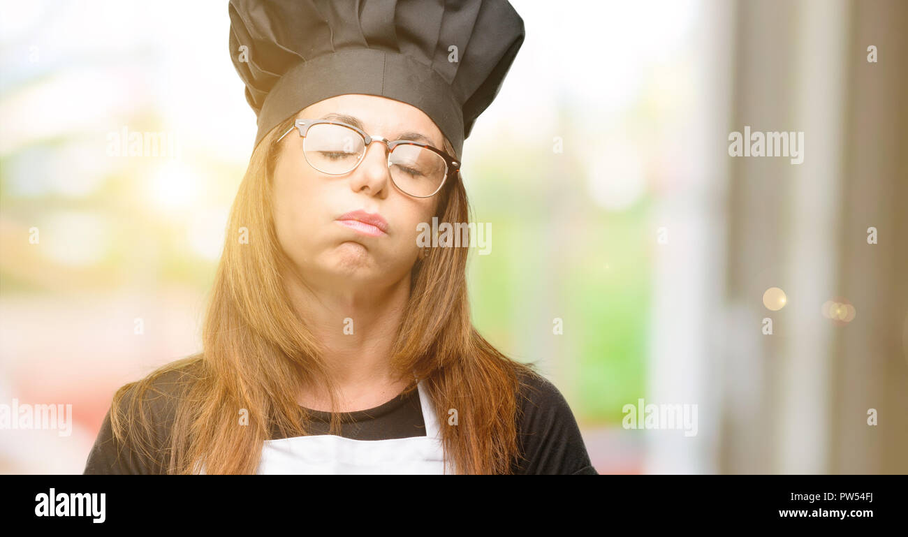 Middle age cook woman wearing chef apron with sleepy expression, being ...