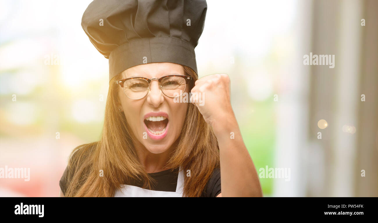 Middle age cook woman wearing chef apron irritated and angry expressing ...
