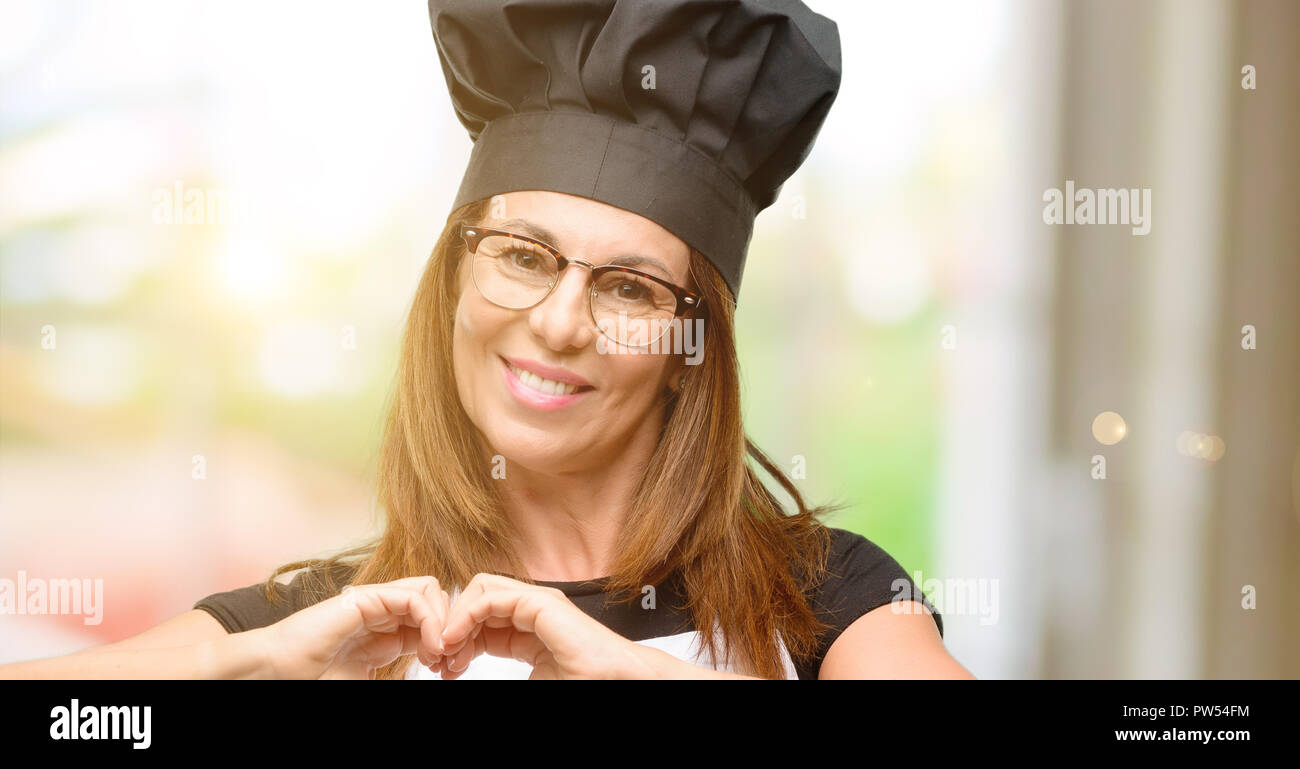 Middle age cook woman wearing chef apron happy showing love with hands ...