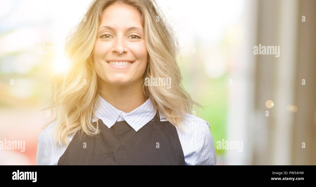 Young shop owner wearing black apron holding blank advertising banner ...
