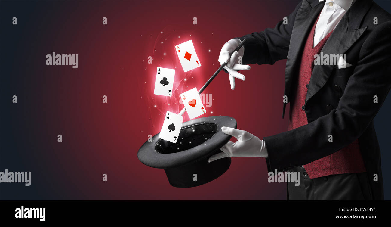 Magician with white gloves conjuring playing cards from a cylinder with ...