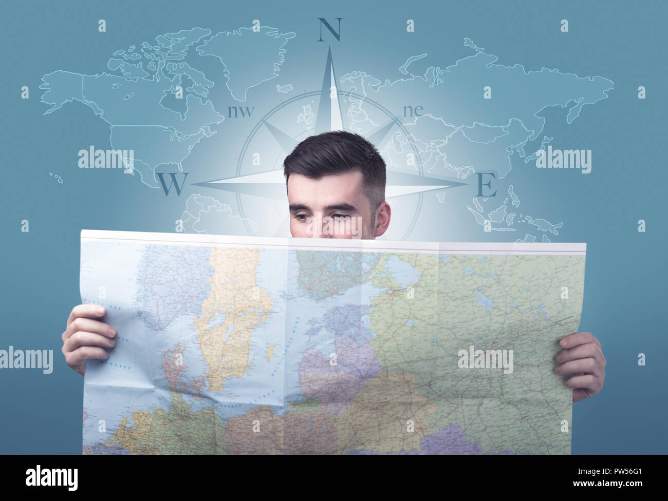 Handsome young man holding a map with a world map and a compass behind ...