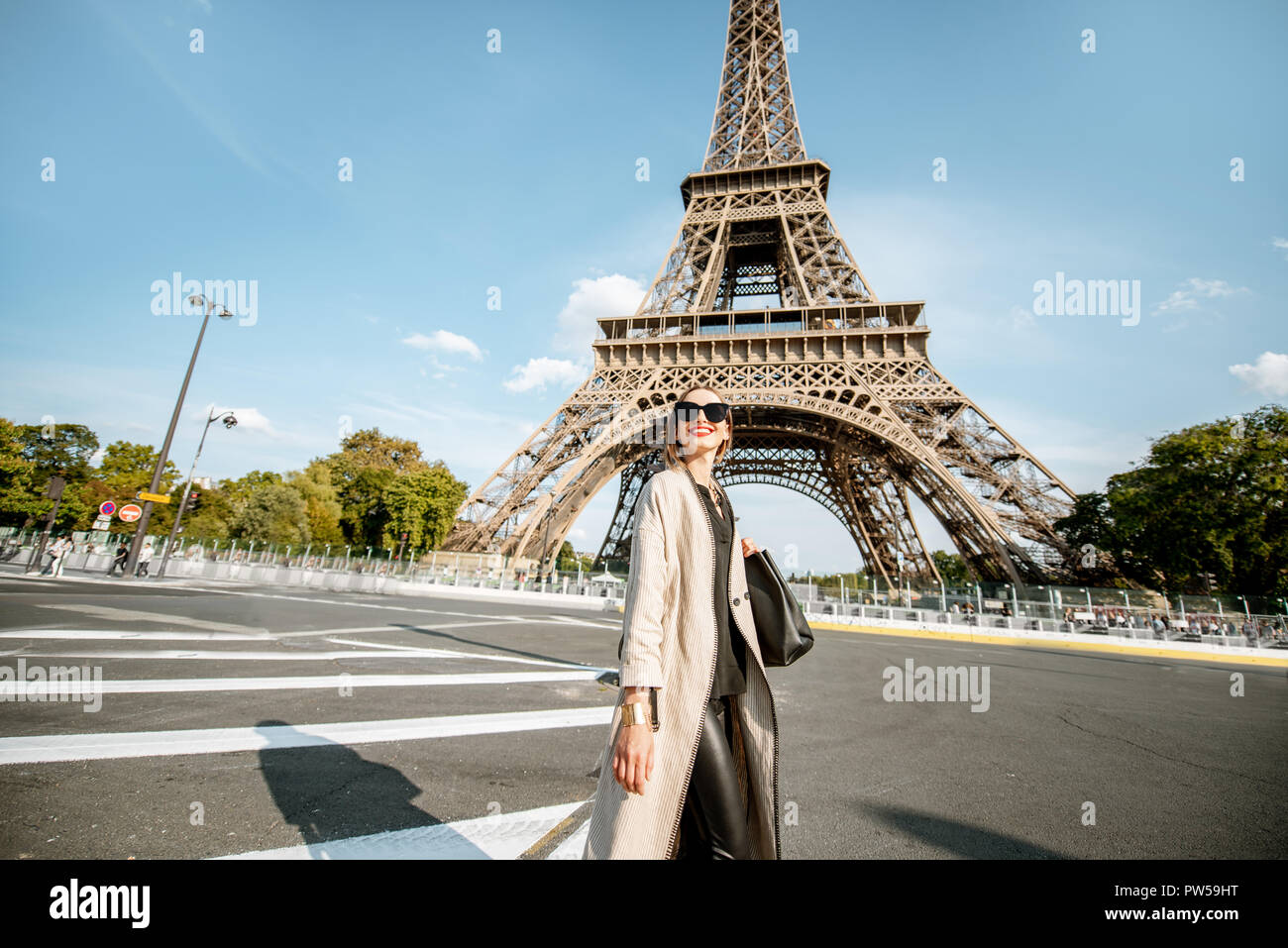 Lifestyle portrait of a young stylish woman crossing the street in front of the famous Eiffel ...