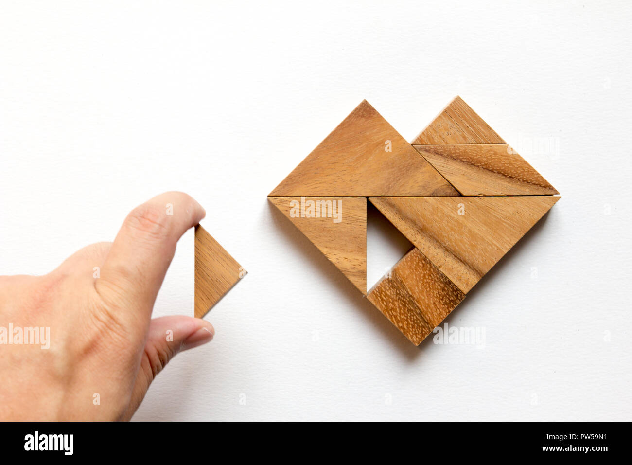 Man held piece of tangram puzzle to fulfill the heart shape on white ...