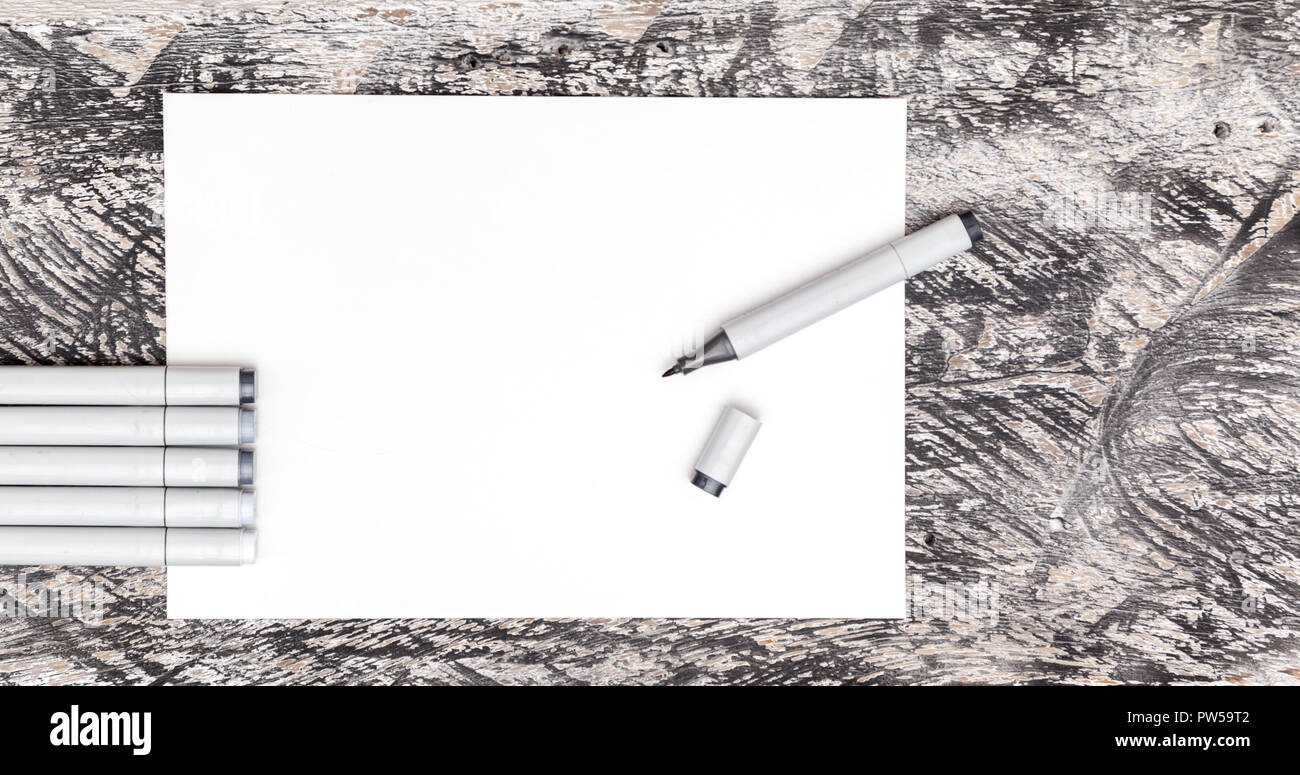 Art markers on white sheet of paper on the surface of a wooden table ...