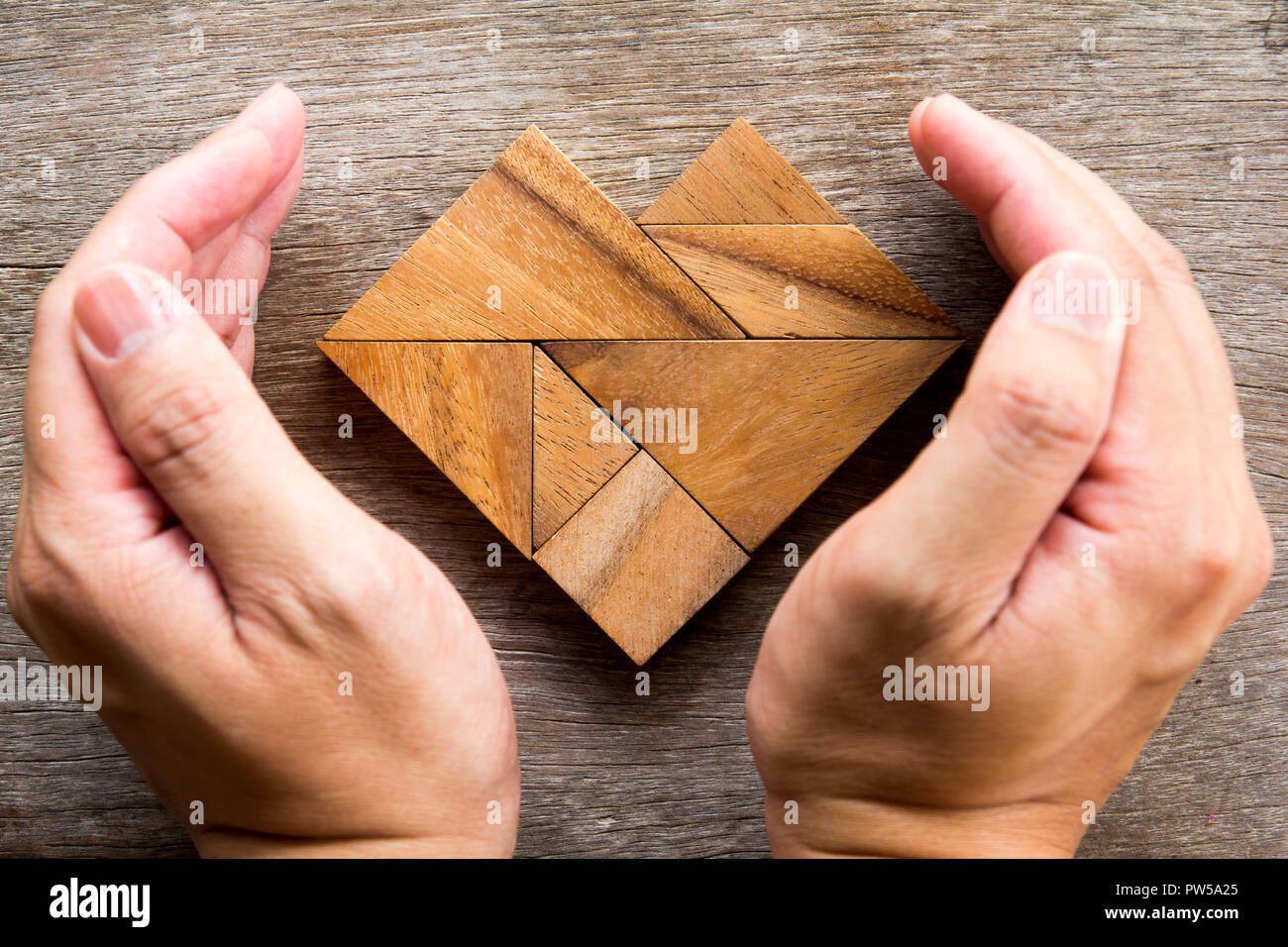 Hand cover tangram puzzle in heart shape on wooden background Stock ...