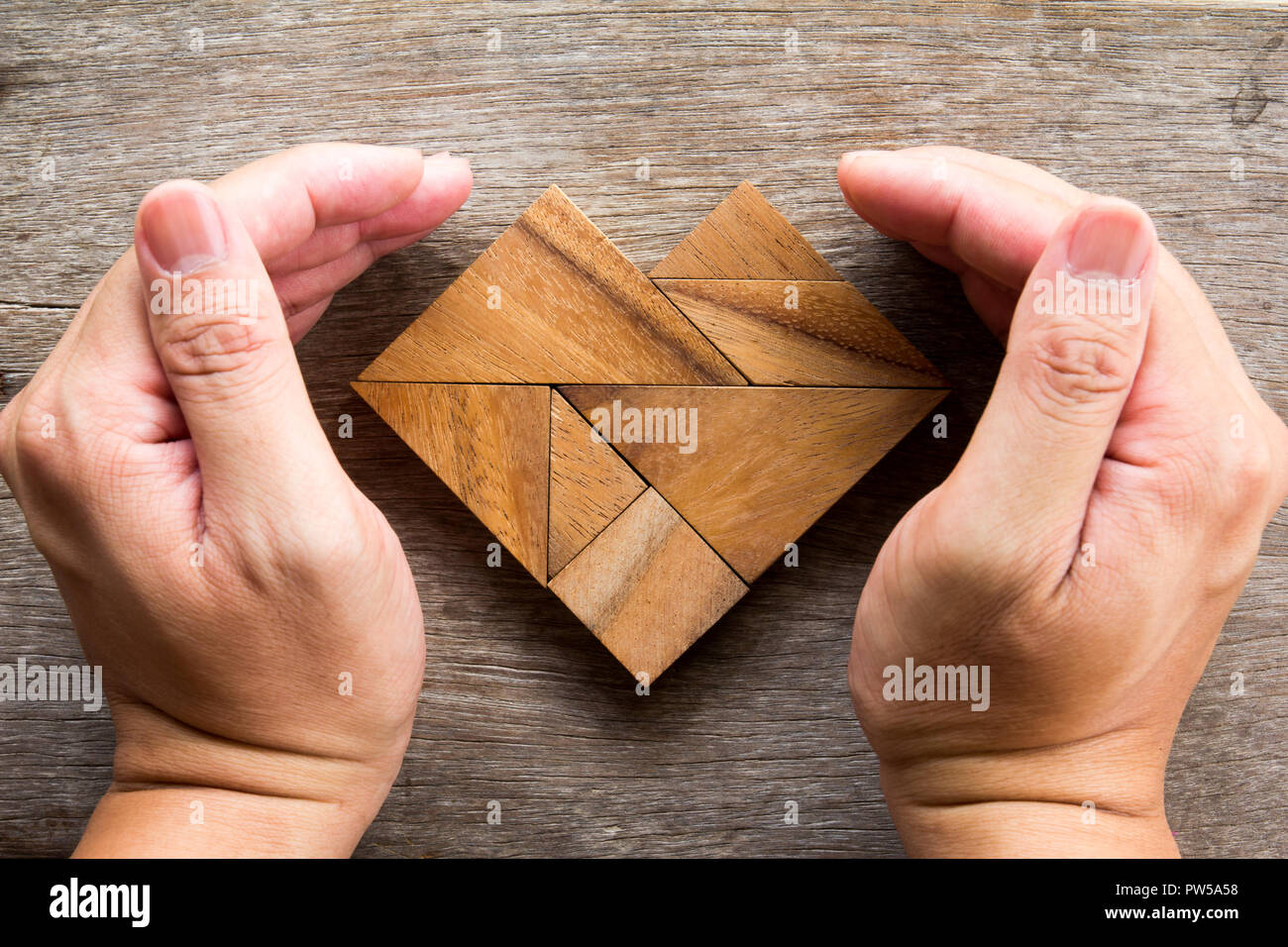 Hand cover tangram puzzle in heart shape on wooden background Stock ...