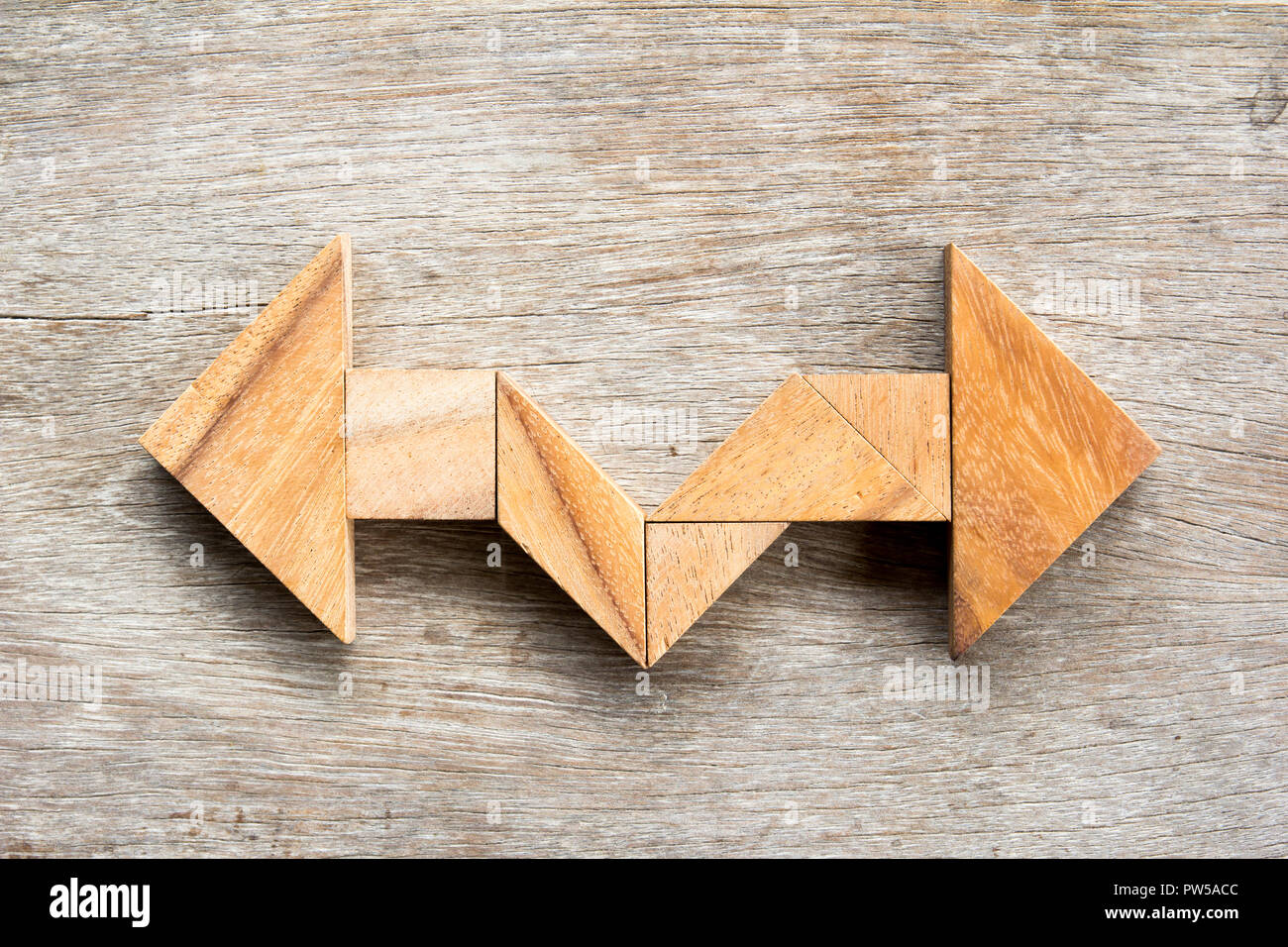 Tangram puzzle as two way arrow shape on wooden background Stock Photo ...