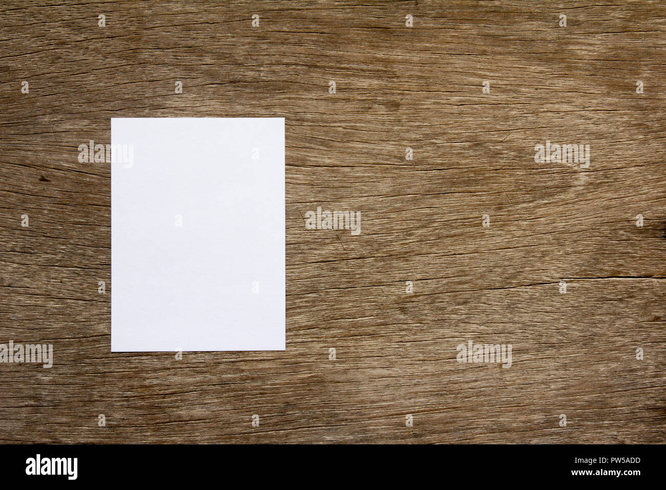 Blank white note paper on brown wooden background for memo or remind ...