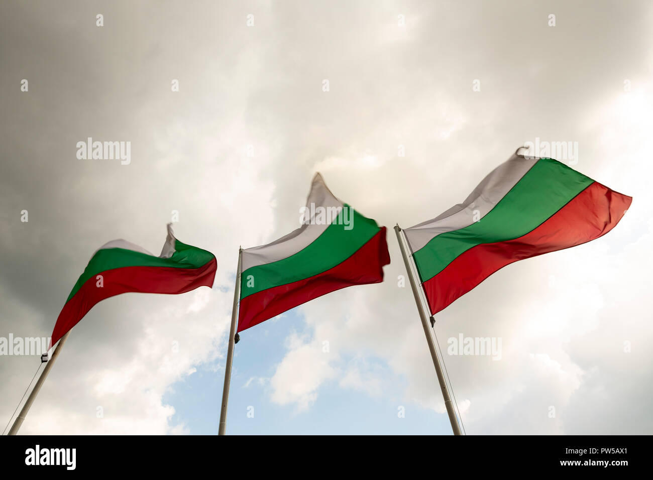 Three Bulgarian national flags wave on pylons aginst the cloudy sky ...
