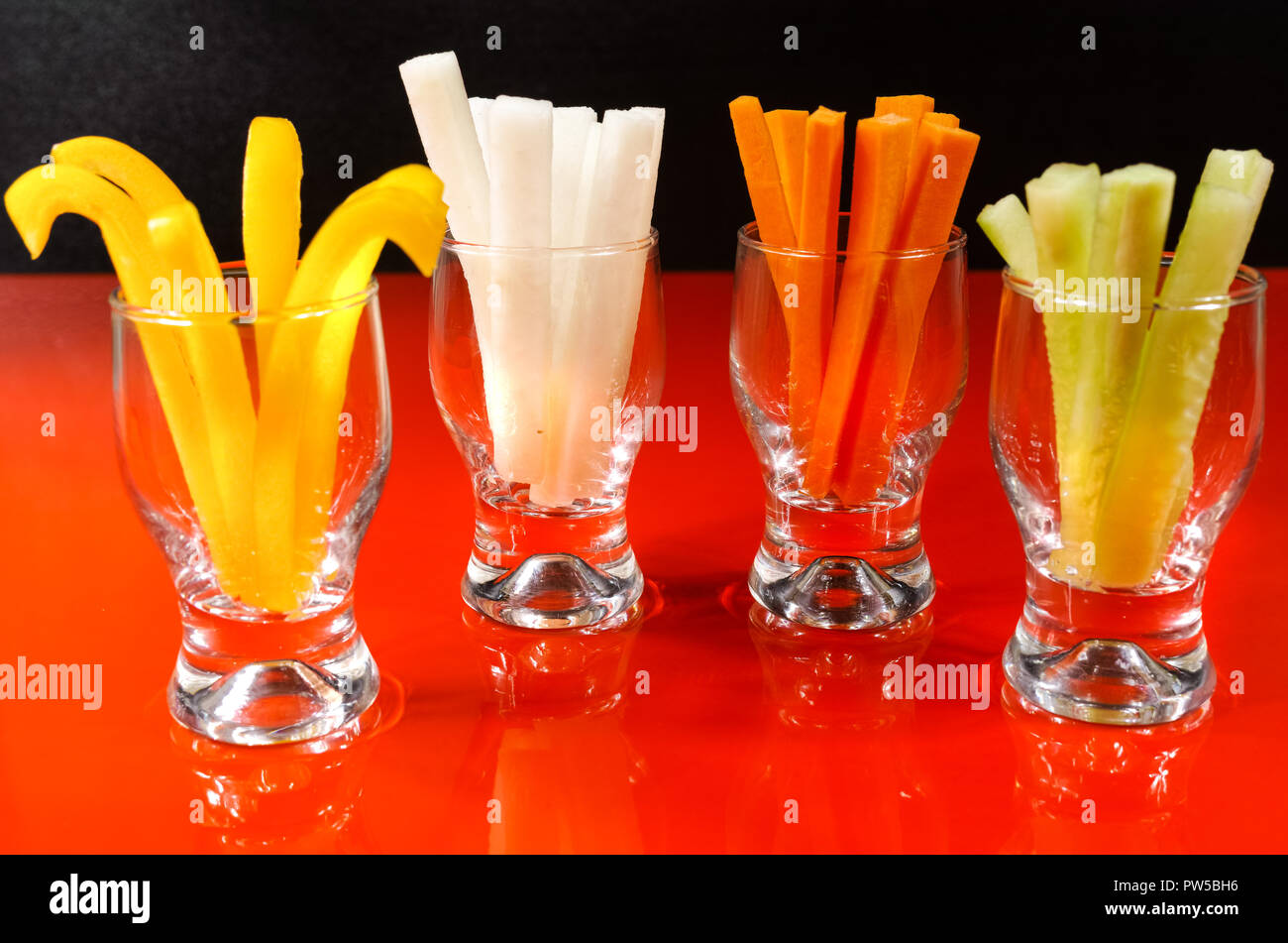 Four types of vegetable sticks, healthy finger food served on red table ...