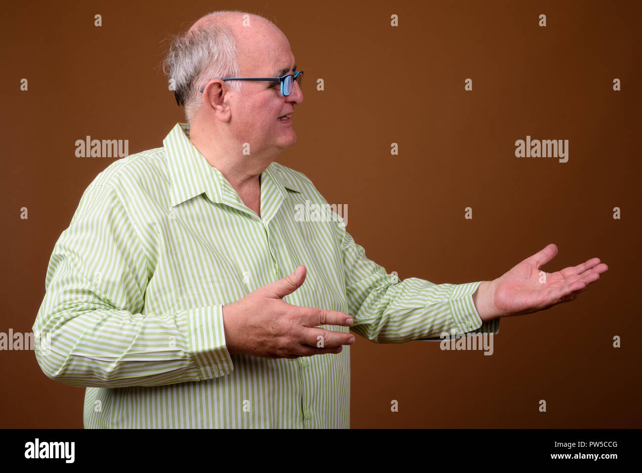 Overweight senior man wearing eyeglasses against brown backgroun Stock ...
