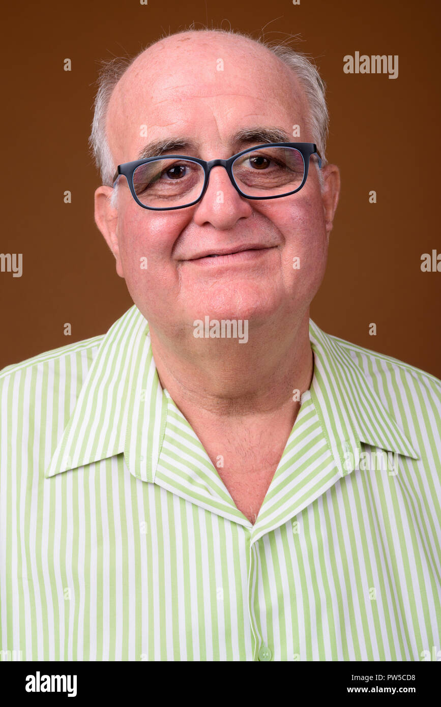 Overweight senior man wearing eyeglasses against brown backgroun Stock ...