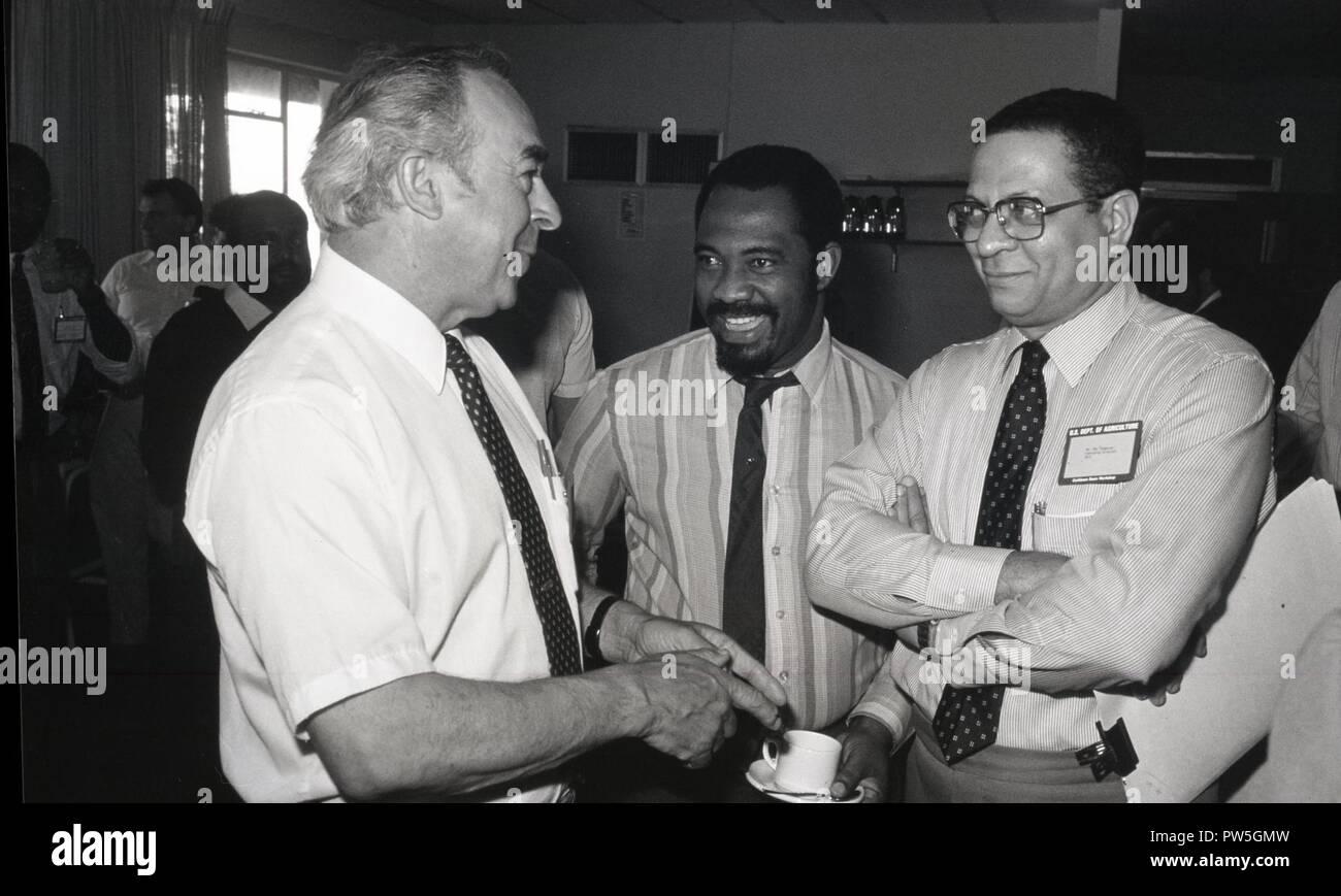 Snapshot of a man talking, while two other men listen, intently Stock ...