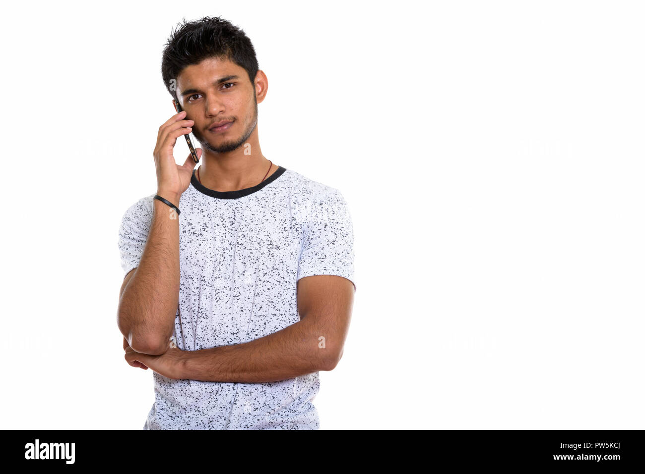 Studio shot of young handsome Indian man talking on mobile phone Stock ...