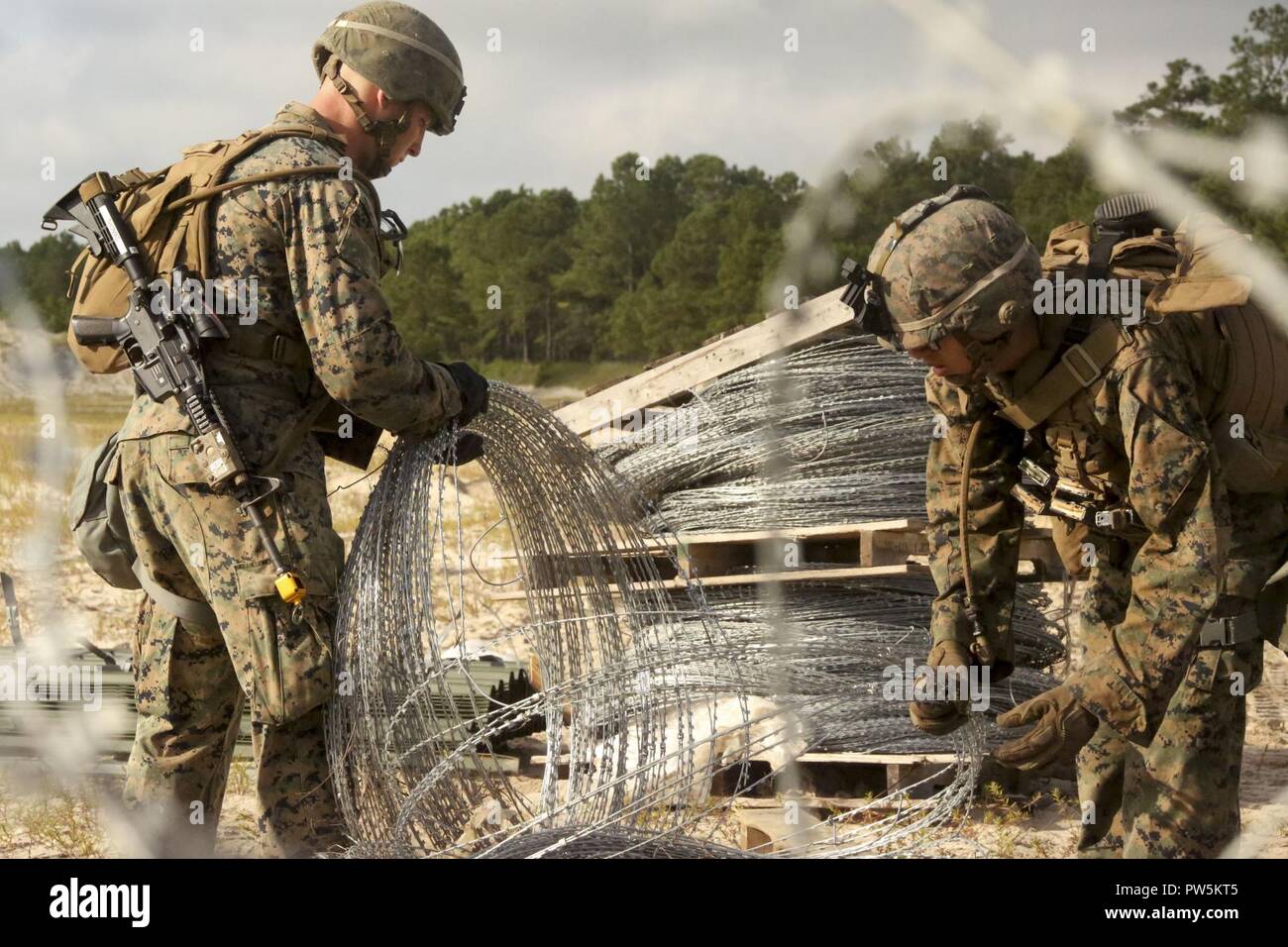 Marines unravel barbed wire to set up a secure boundary during a field ...