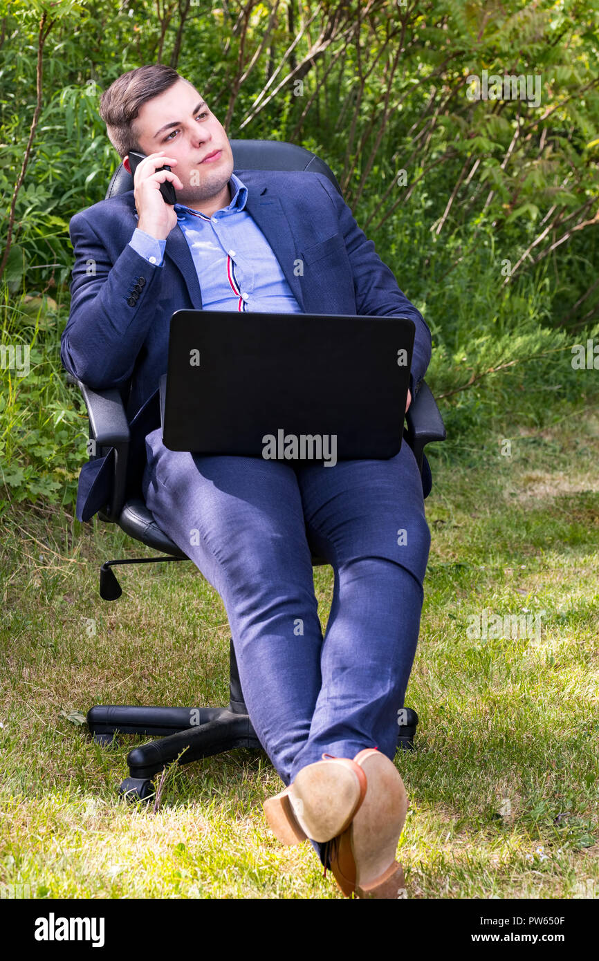 Young business man or entrepreneur with laptop and smartphone working ...