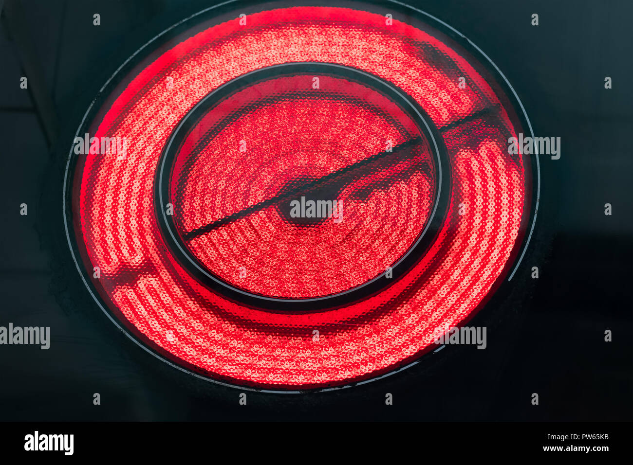 Closeup of modern electric stove burner glowing red. Black background ...