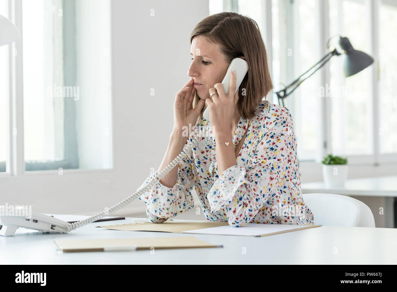 Serious young business woman making a phone call as she sits at her ...