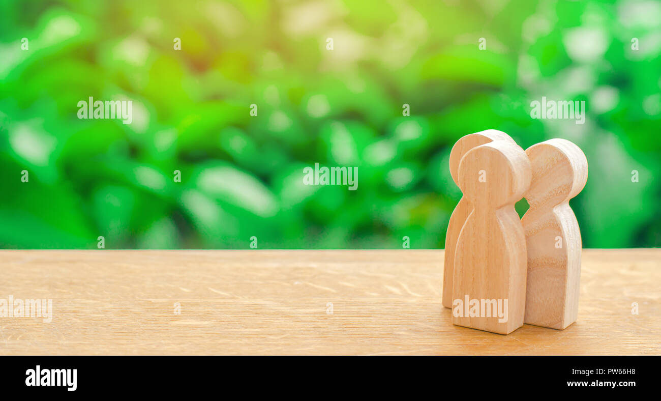 Three people stand together and talk. Three wooden figures of people ...