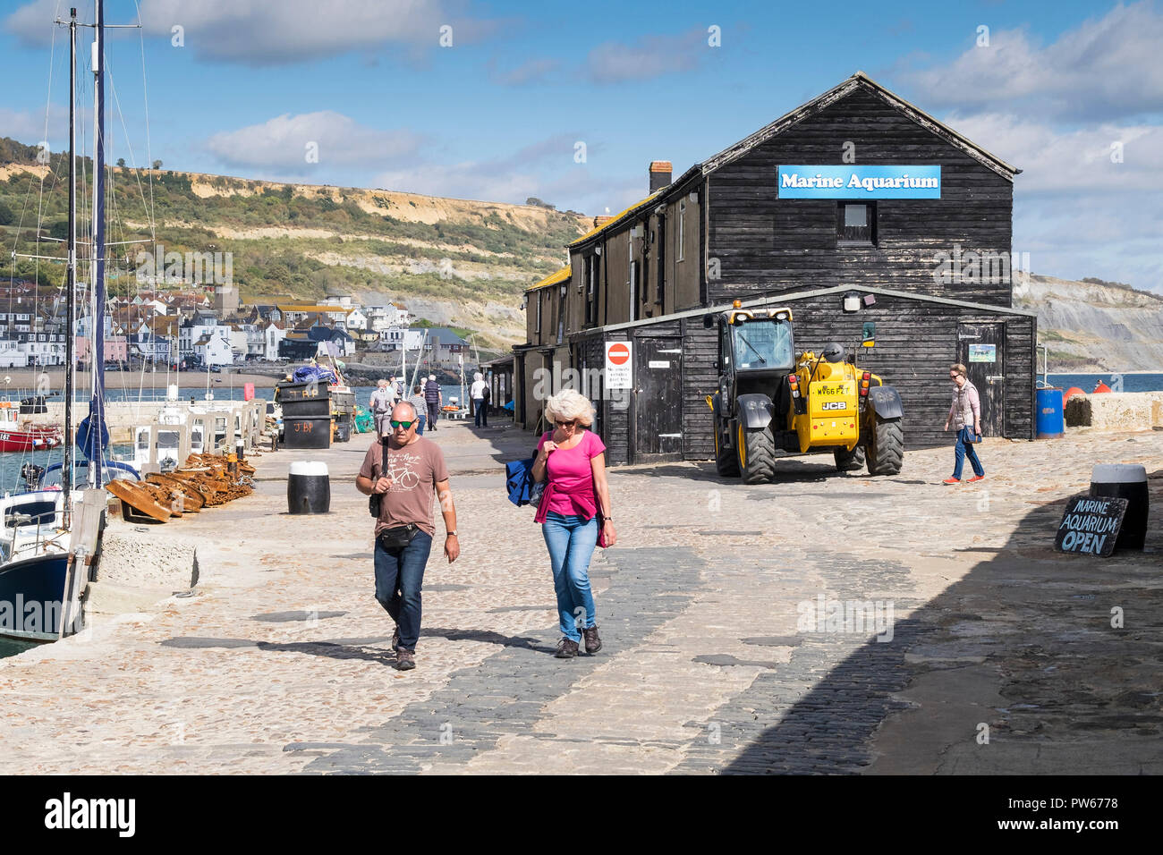 People walking on The Cobb in the coastal town of Lyme Regis in Dorset ...