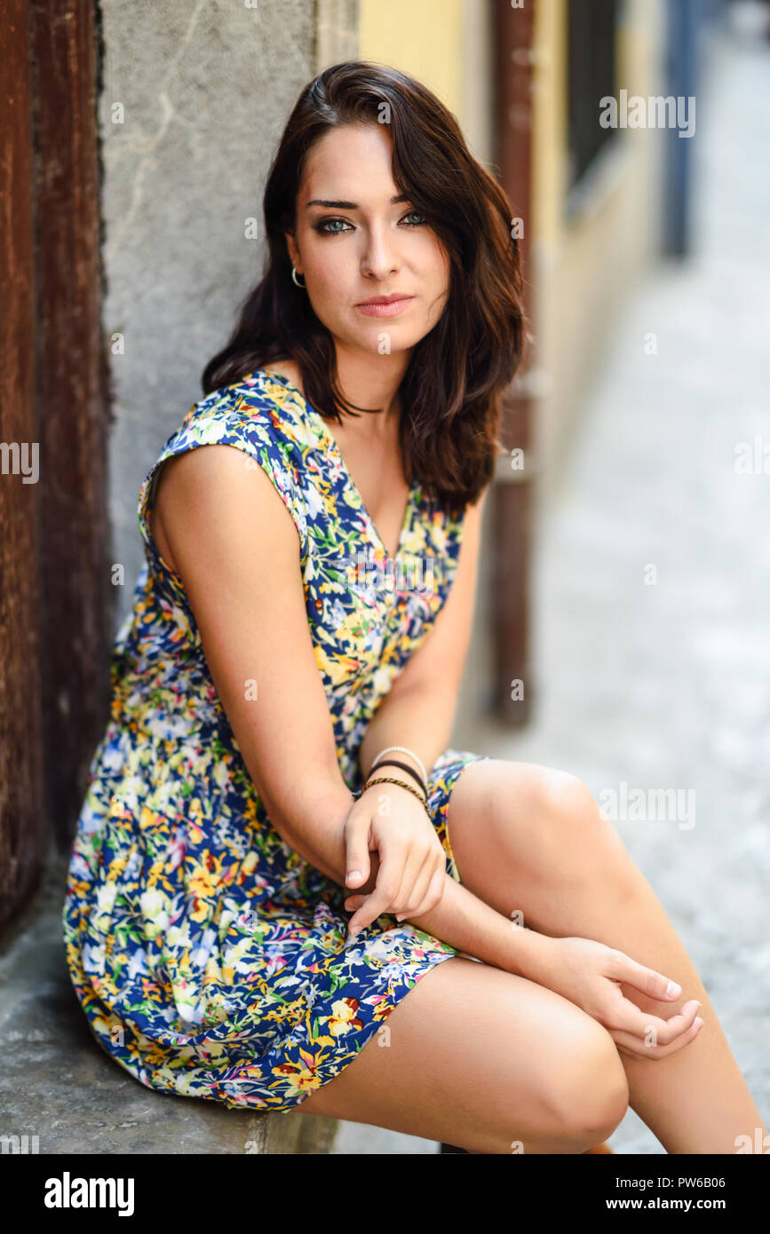 Beautiful young woman with blue eyes sitting on urban step. Girl ...