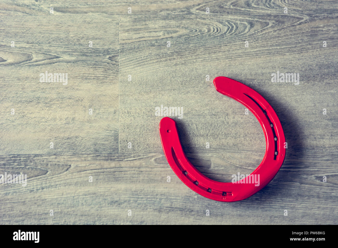 Single red horseshoe on a wooden desk Stock Photo - Alamy