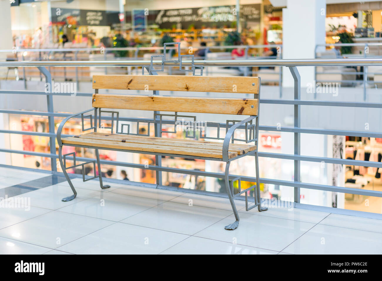 A wooden bench in the mall. Wooden bench and trash can in the shopping ...