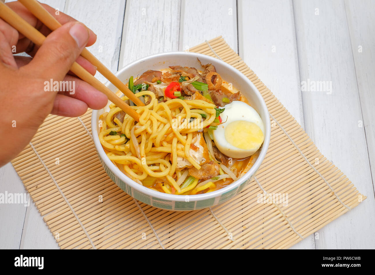 Malay Mee Rebus in the bowl with chopsticks on white table This dish is ...