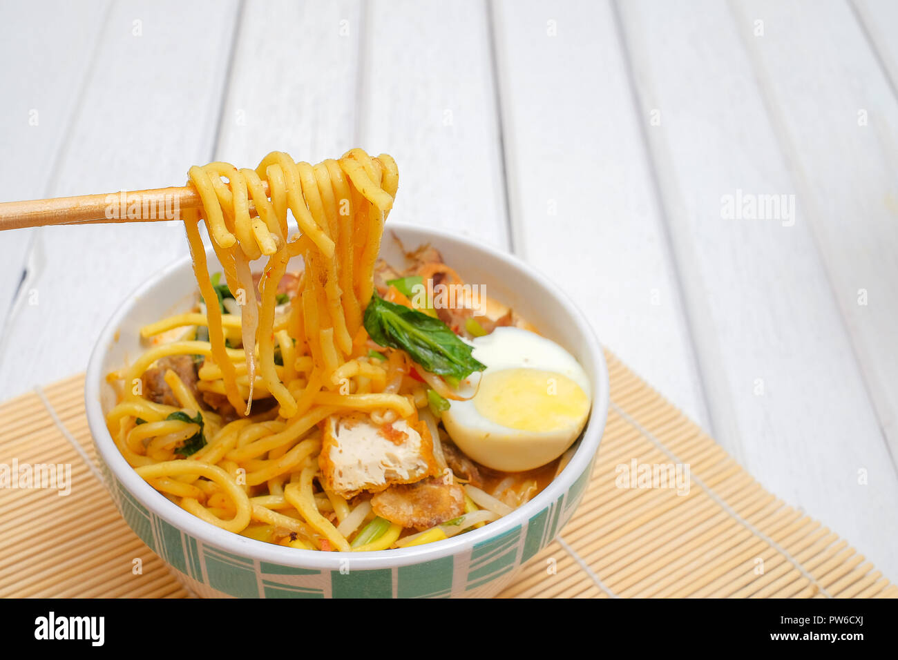 Malay Mee Rebus in the bowl with chopsticks on white table This dish is ...