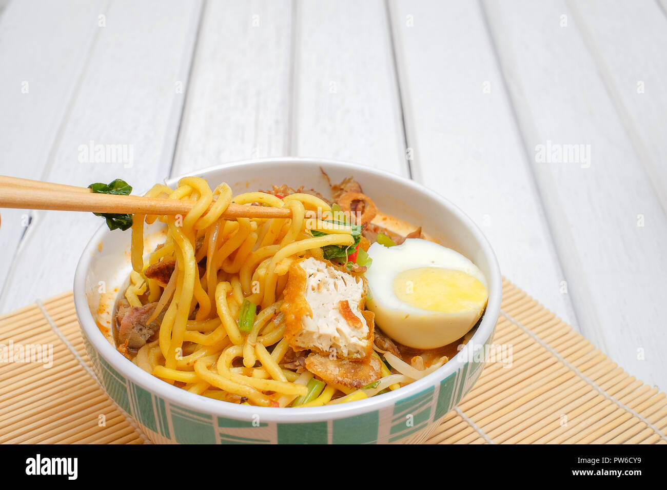 Malay Mee Rebus in the bowl with chopsticks on white table This dish is ...