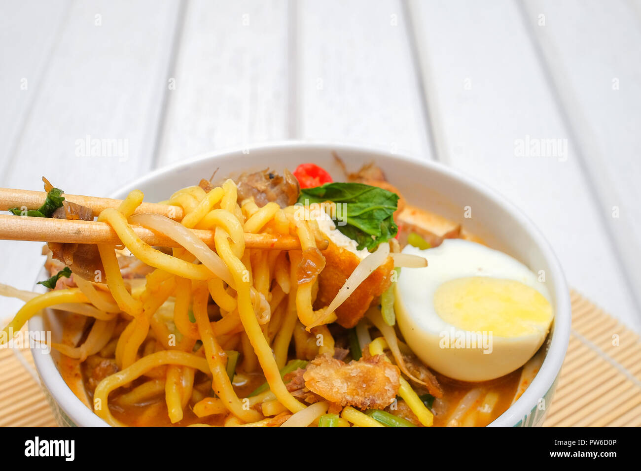 Malay Mee Rebus in the bowl with chopsticks on white table This dish is ...
