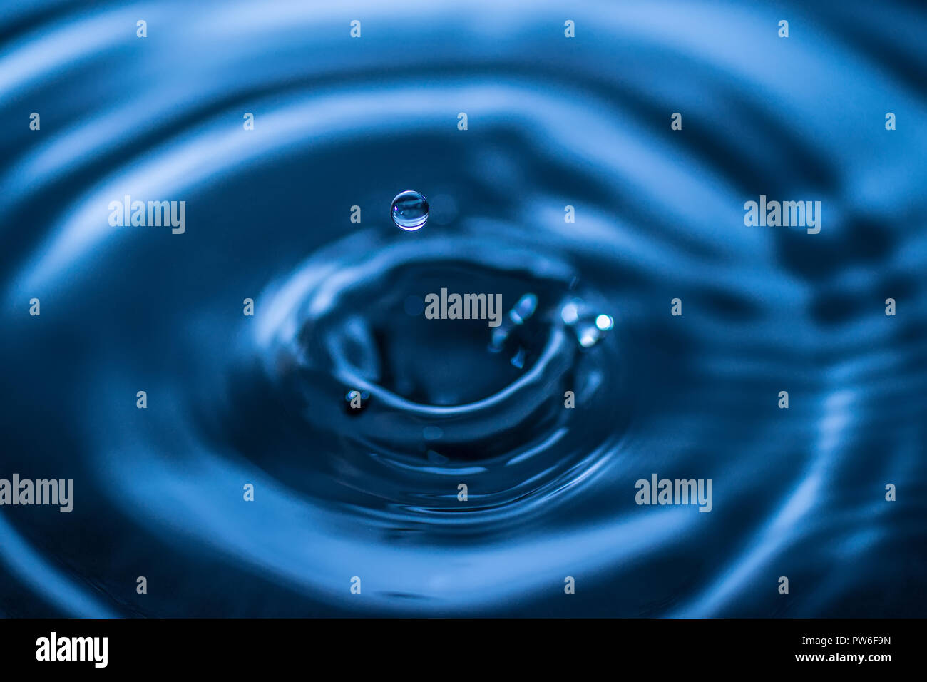 water drop splash in a glass blue colored Stock Photo - Alamy