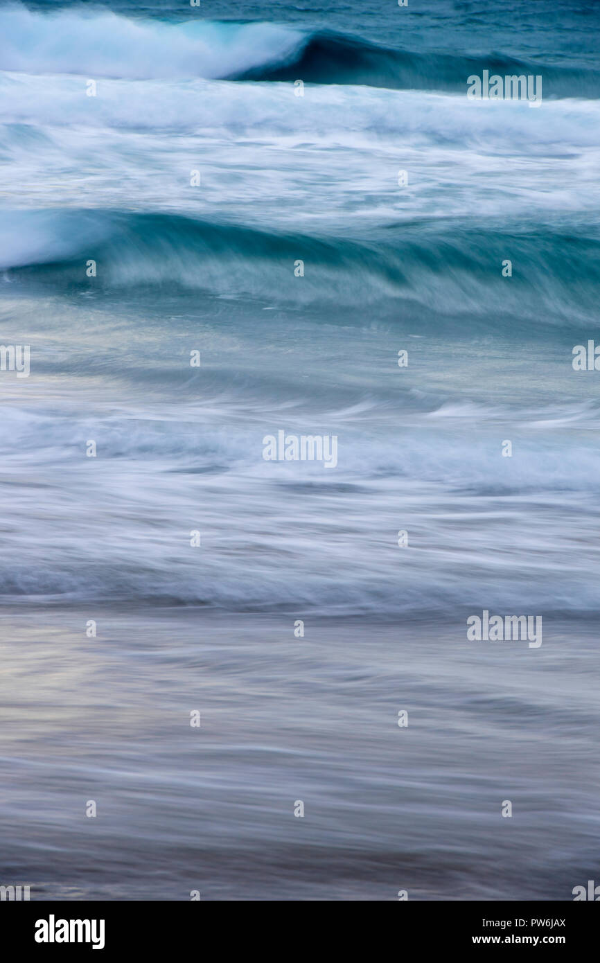 Long exposure of waves and the incoming tide splashing onto a sandy ...