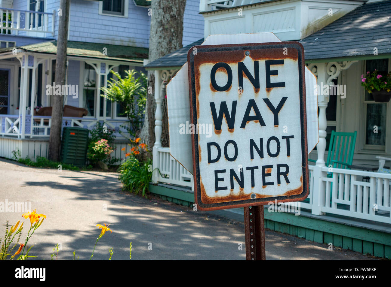 suburban black and white rusted street sign with white fenced porches ...
