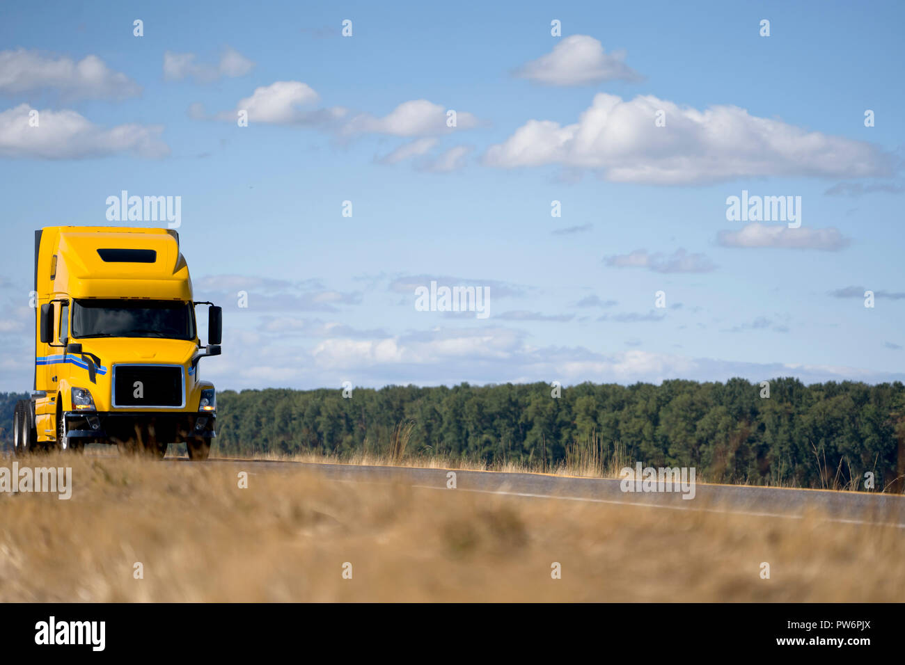 Big rig yellow semi truck tractor without of semi trailer going on the ...