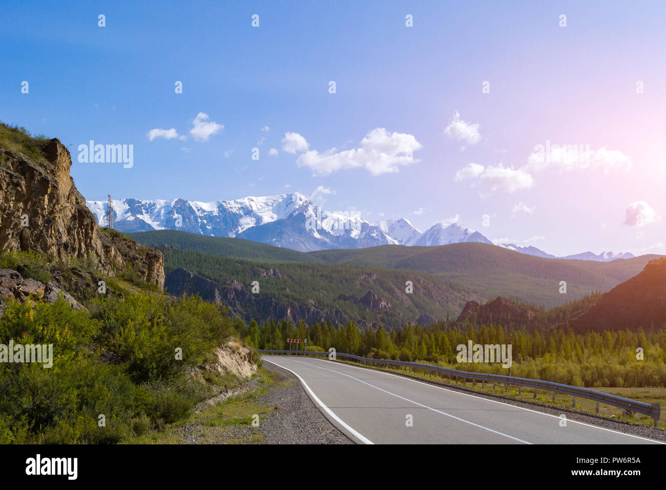 Winding asphalt road near the cliff against the backdrop of high snow ...
