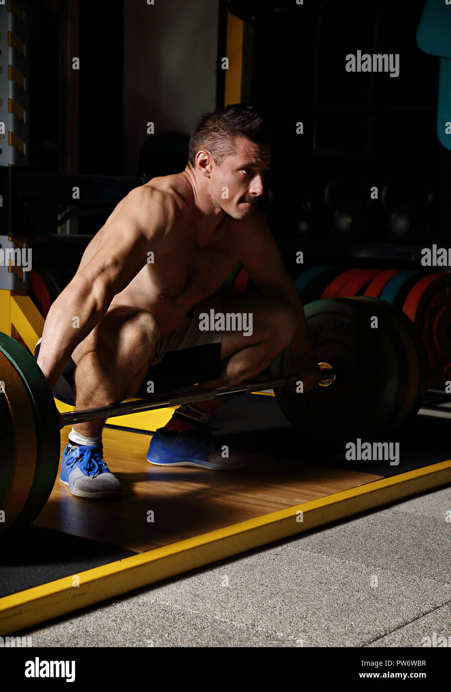 Handsome strong man lifting barbell in crossfit gym and lookin serious ...