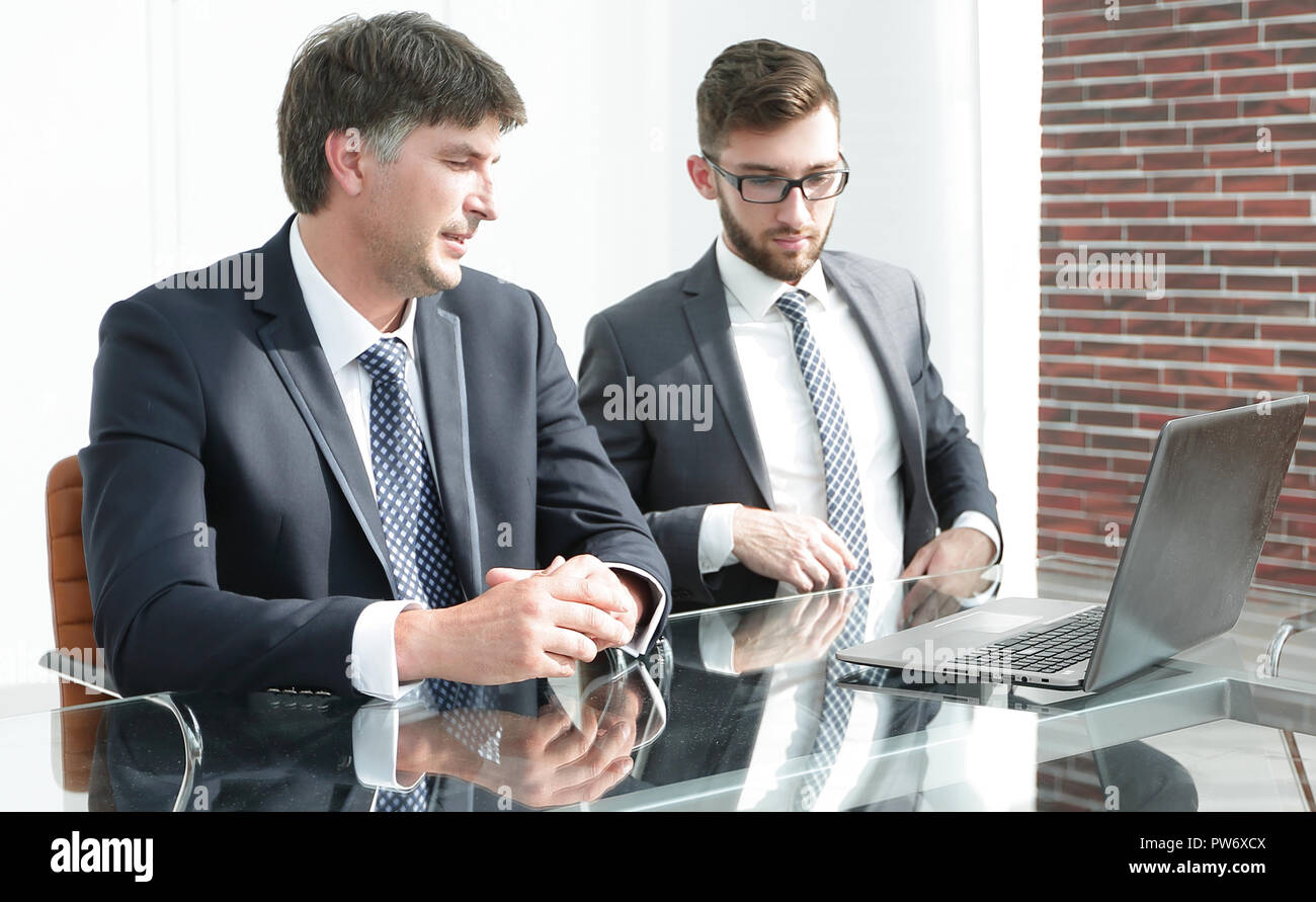 Portrait of two business people sitting at office desk Stock Photo - Alamy