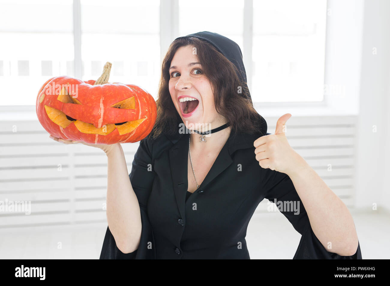 Halloween concept - Happy witch showing thumbs up gesture with pumpkin ...