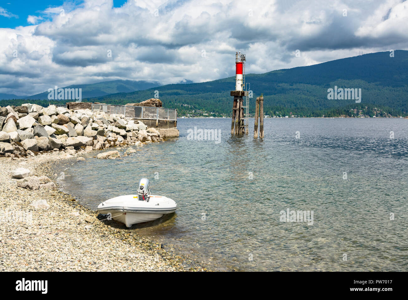 Motorized boat moored at stone shore with ship channel light behind ...