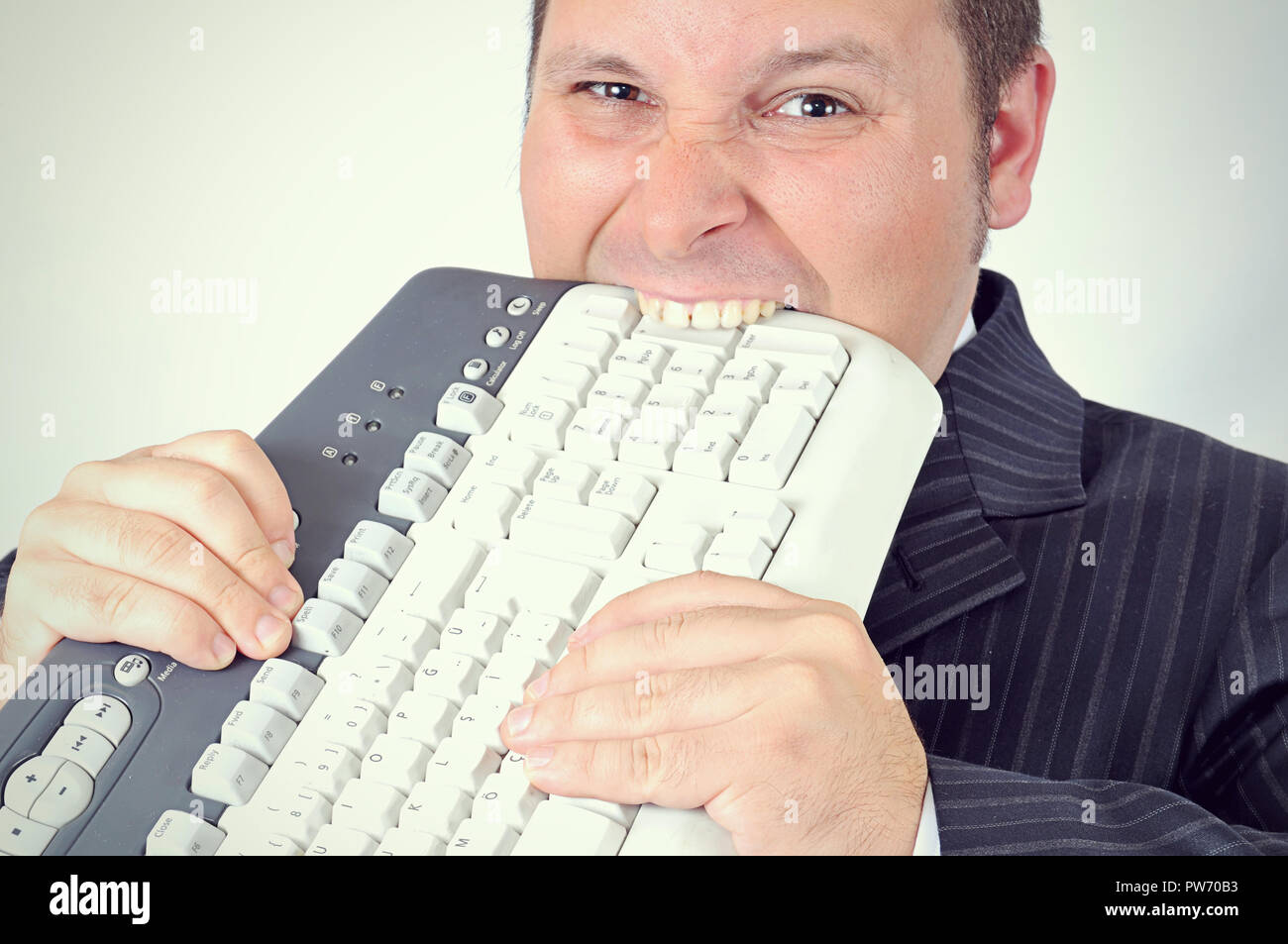 Businessman is biting the computer keyboard Stock Photo - Alamy