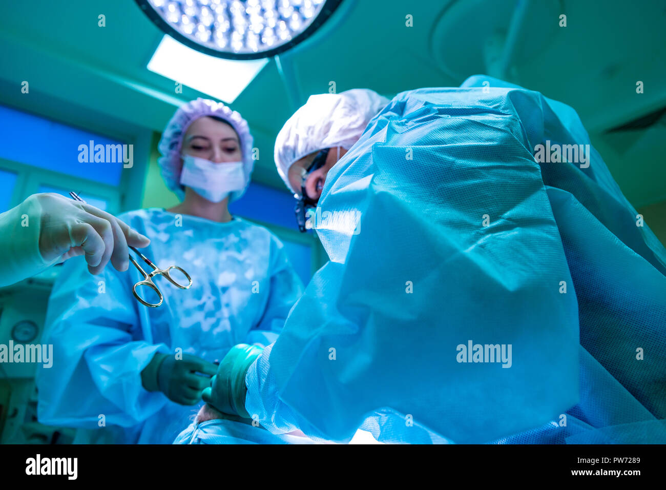 Surgeon and his assistant performing cosmetic surgery on nose in ...