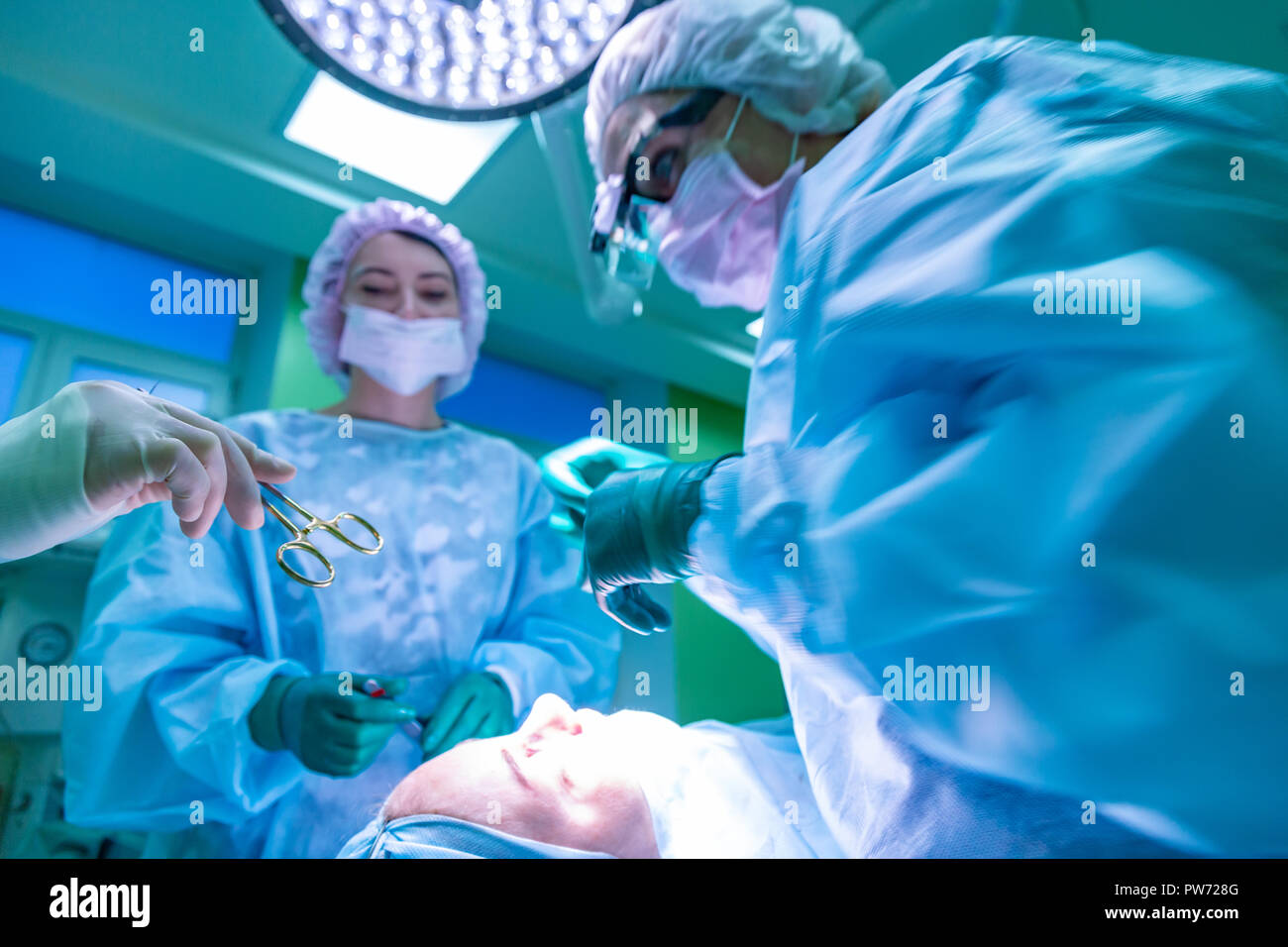 Surgeon and his assistant performing cosmetic surgery on nose in ...