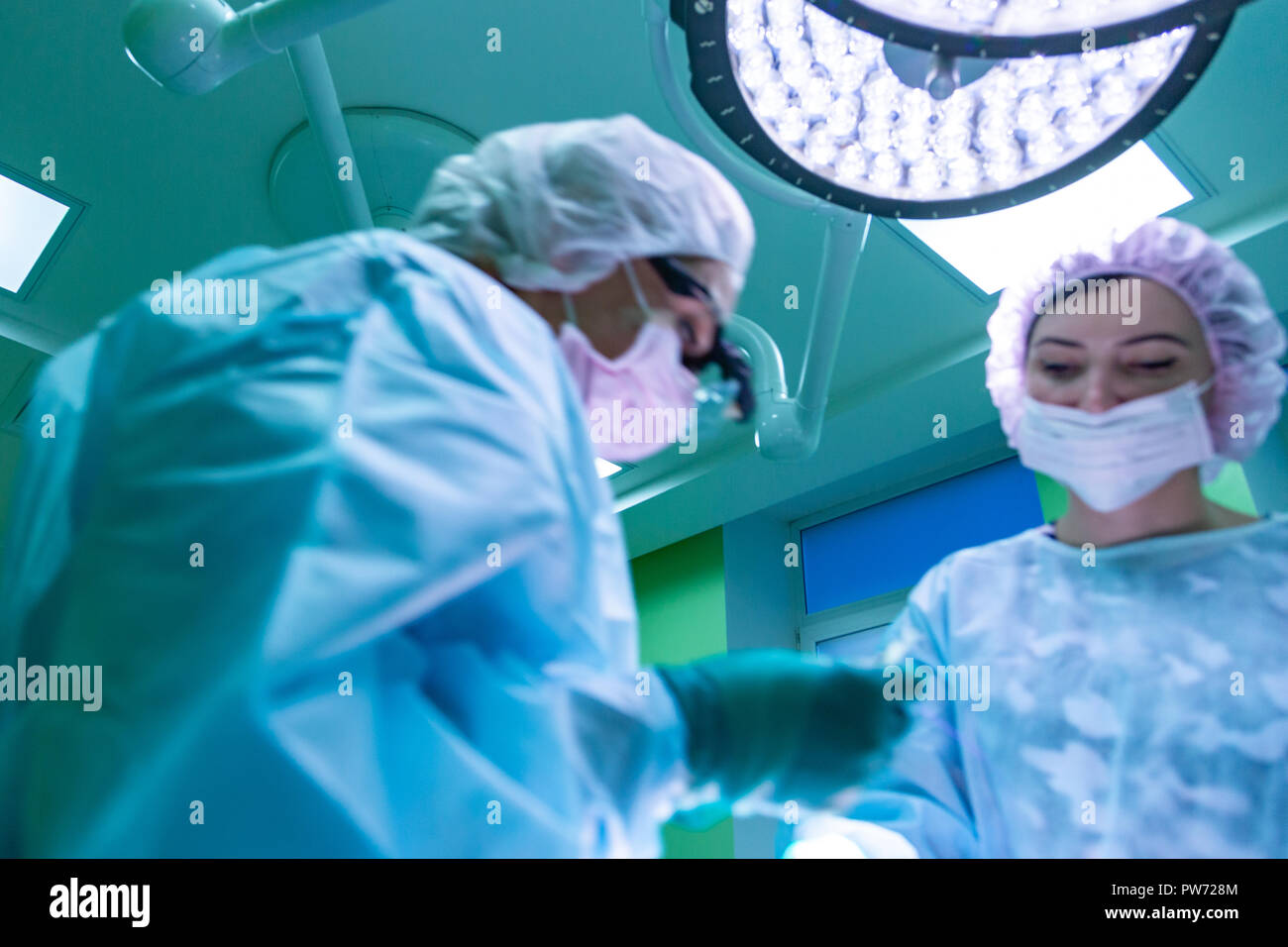 Surgeon and his assistant performing cosmetic surgery on nose in ...