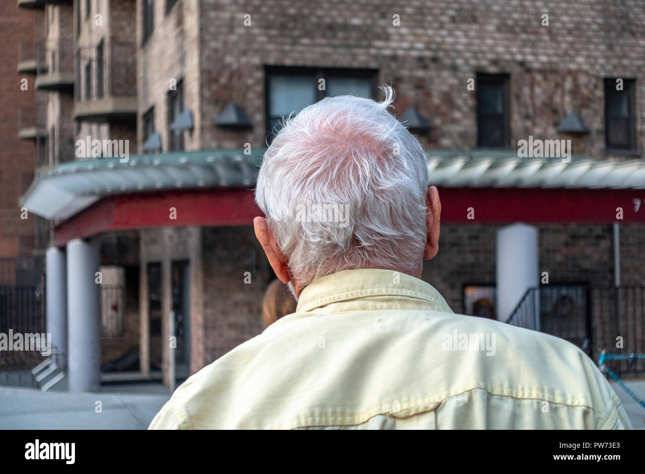back of a senior citizen man walking the streets of an uraban city with ...